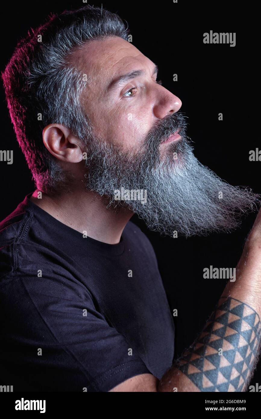 Side view of handsome mature male with gray beard on black background ...
