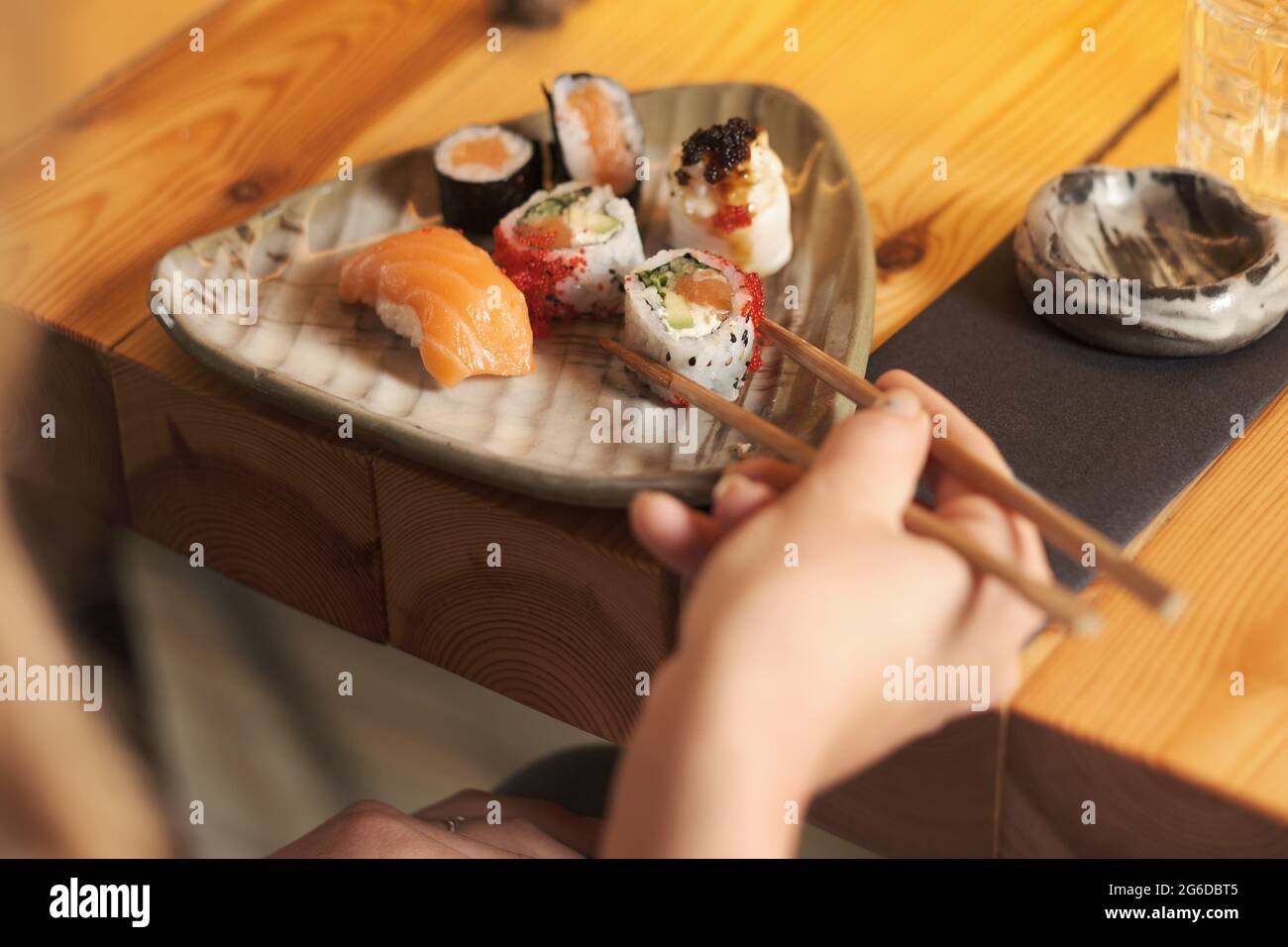 From above cropped unrecognizable female eating tasty sushi in Japanese ...