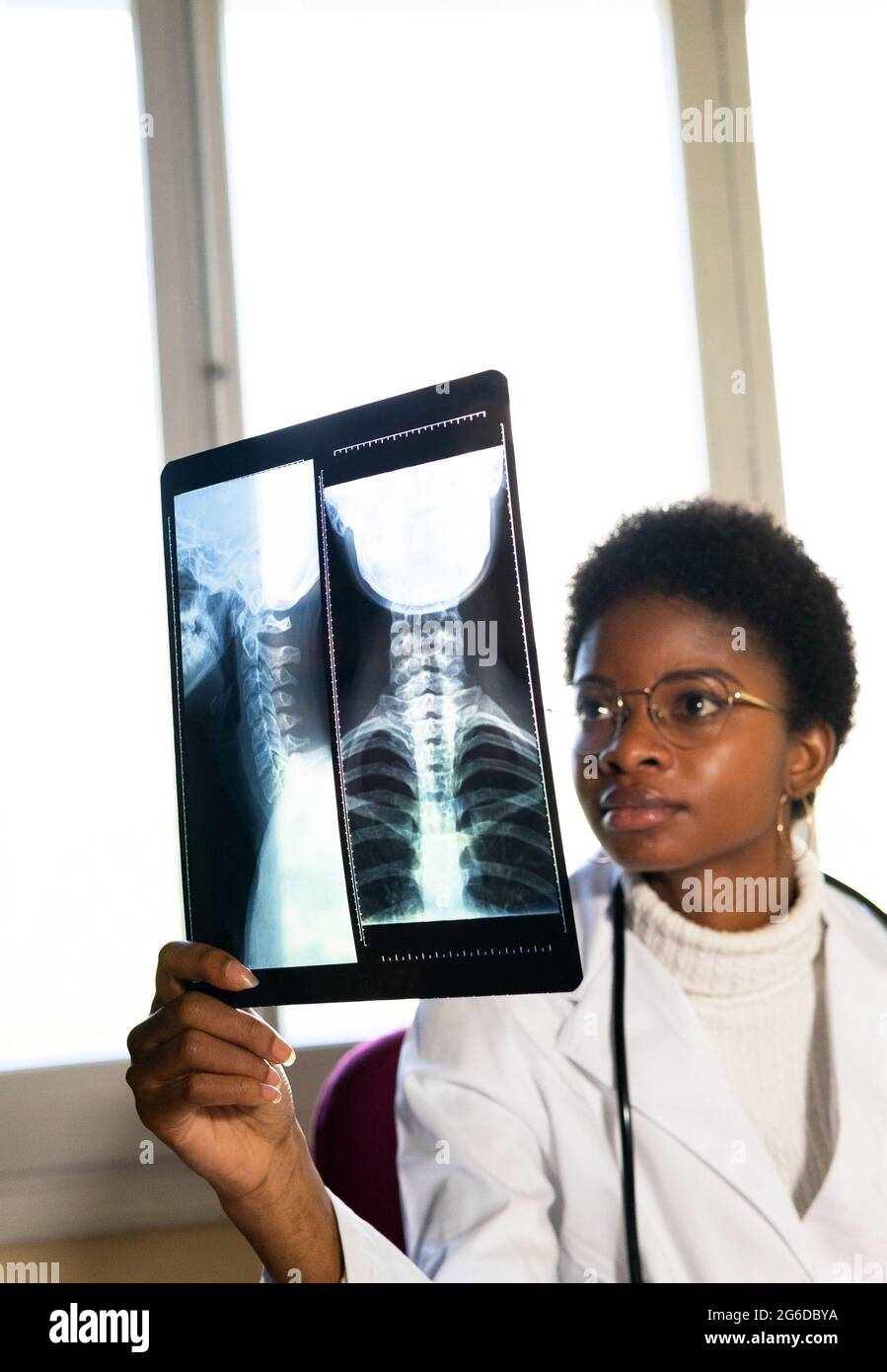 Young black female medic standing near window and examining x ray scan ...