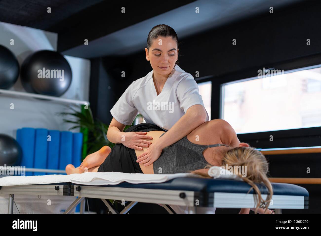 Female therapist in white robe massaging back of Woman during ...