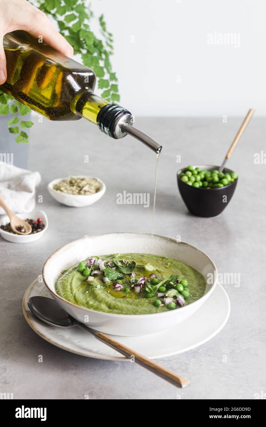 Anonymous person pouring olive oil over Delicious peas cream over ...