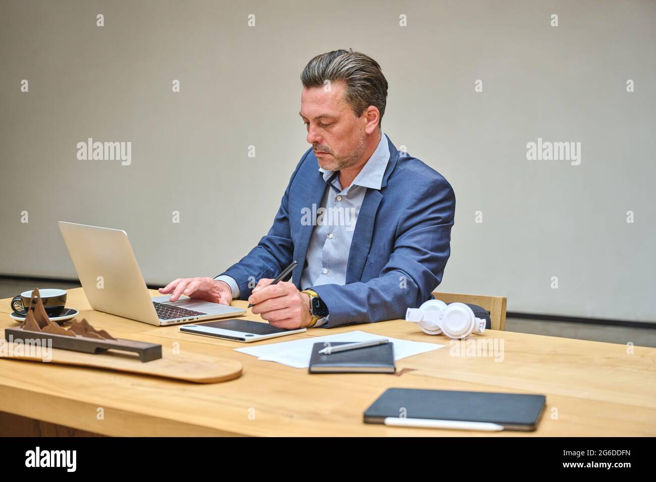 Designer at his desk working on his computer using his tablet Stock ...