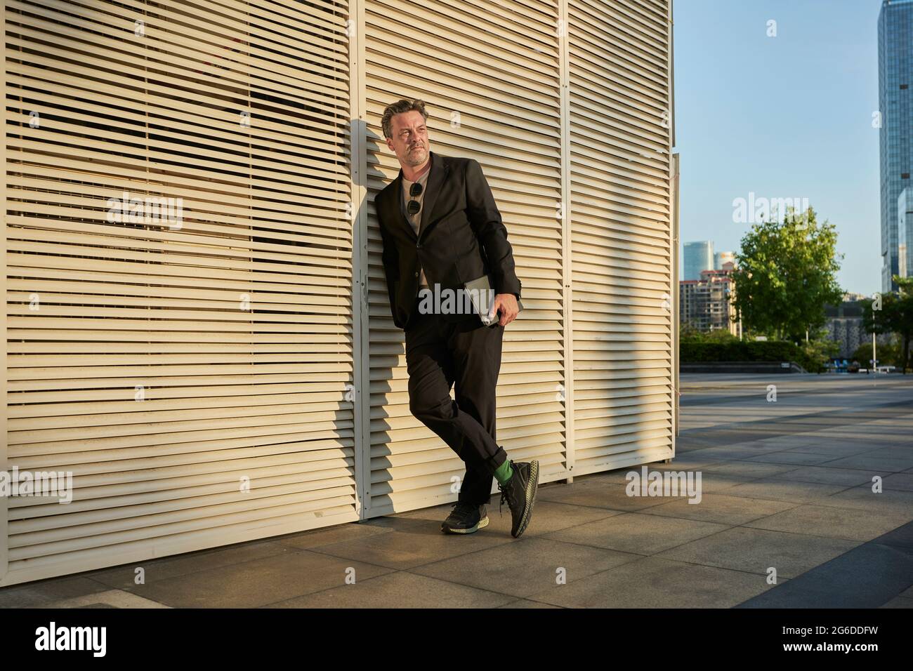 Business man standing up outside of office building in sunset time ...