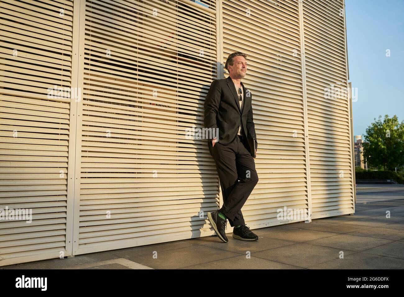 Business man standing up outside of office building in sunset time ...