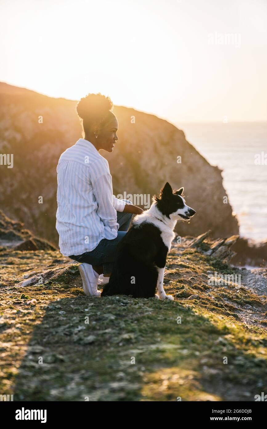 Side view of young African American female owner with Border Collie dog ...