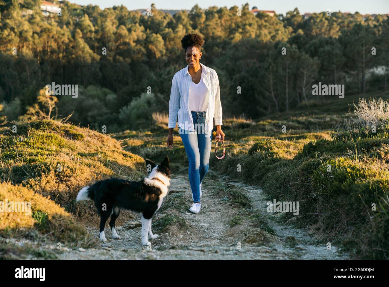 Full body of happy ethnic Woman with Border Collie dog walking together ...