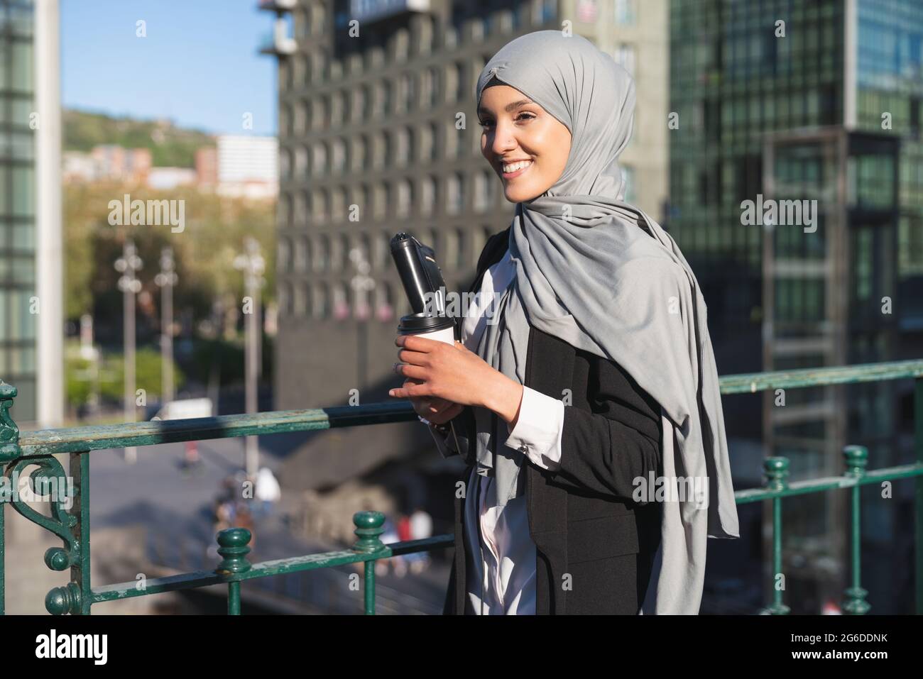 Cheerful Muslim female entrepreneur in hijab and with takeaway coffee ...
