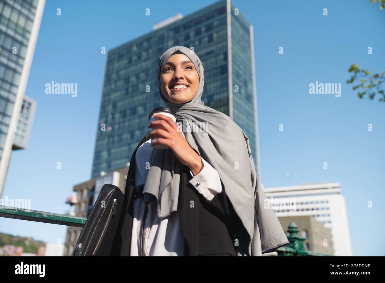 From below cheerful Muslim female entrepreneur in hijab and with ...
