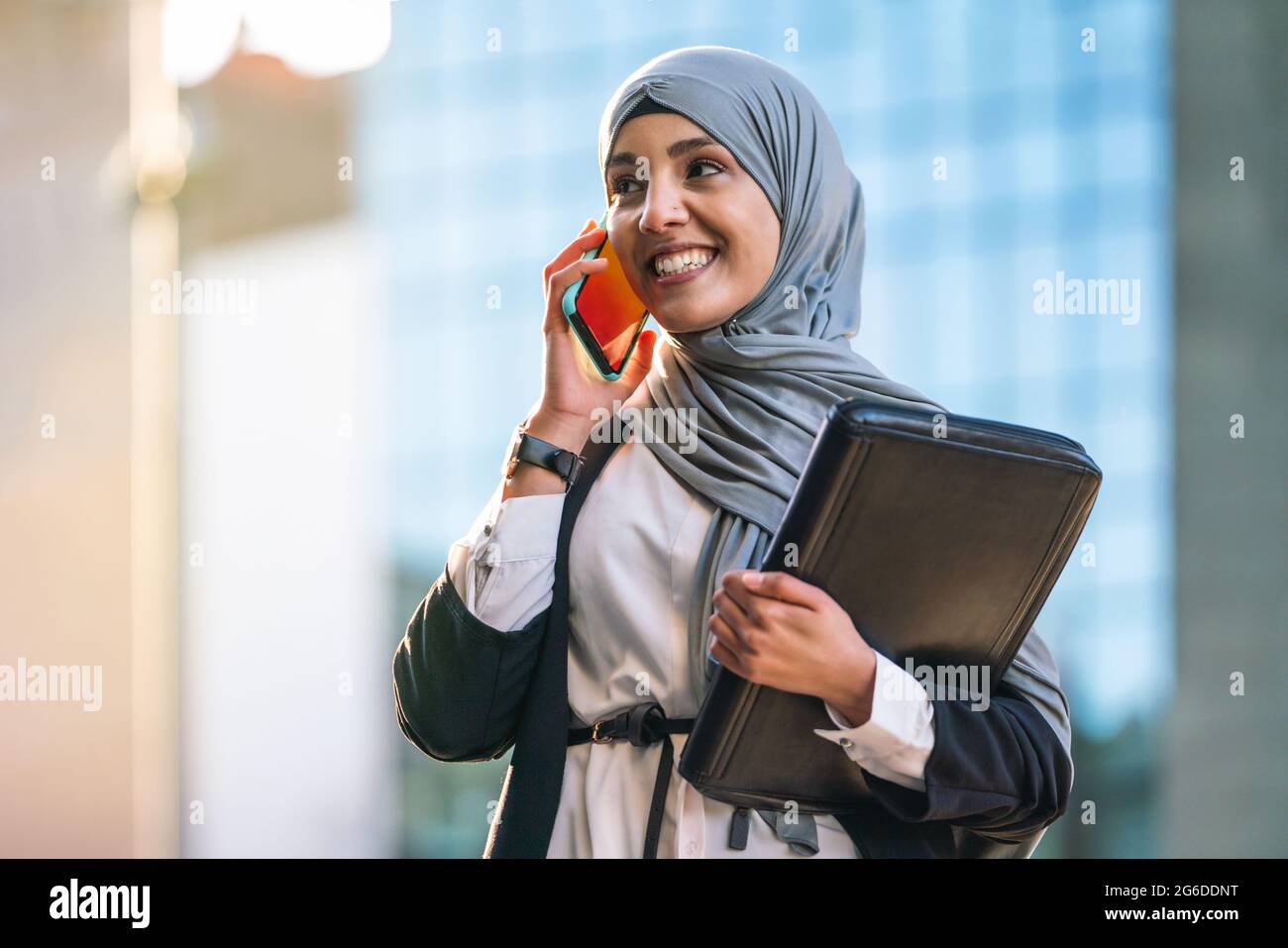 Content Muslim female entrepreneur in hijab and with folder standing in ...