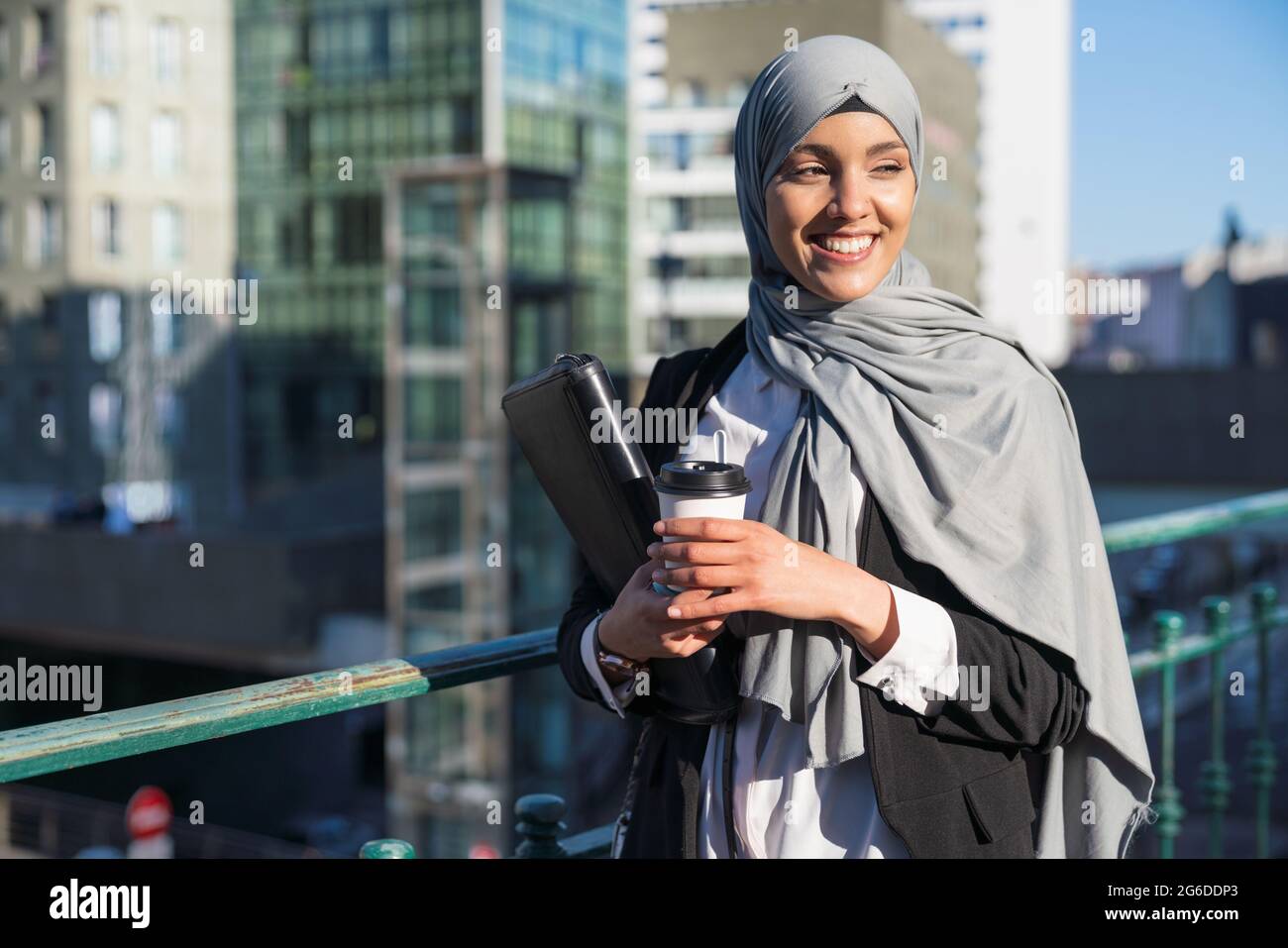 Cheerful Muslim female entrepreneur in hijab and with takeaway coffee ...
