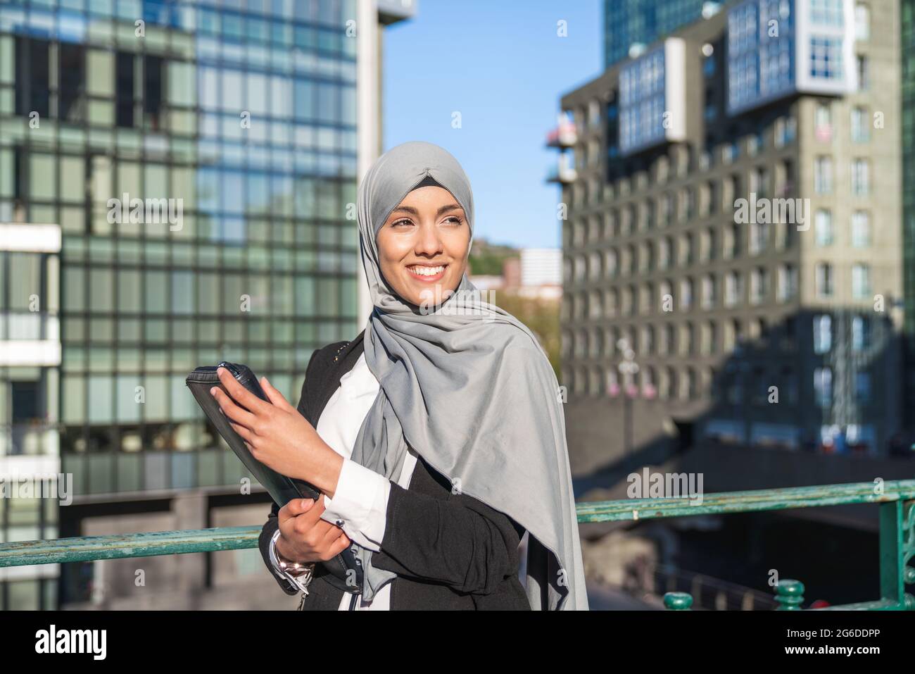 Cheerful Muslim female entrepreneur in hijab and with takeaway coffee ...