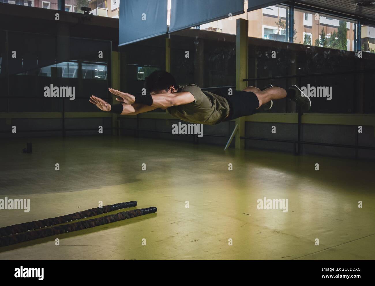 Focused Asian boy training with battle rope in modern crossfit gym ...
