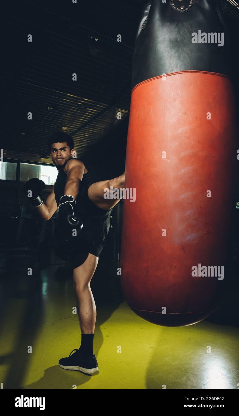 Young focused Asian man training kick boxing performing strike kicks ...