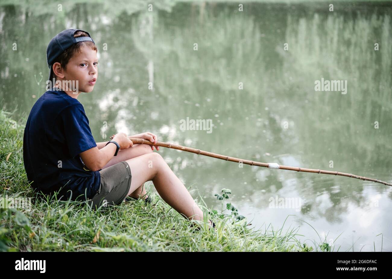 A boy holding a fishing rod and fishing in the lake, summer activities ...