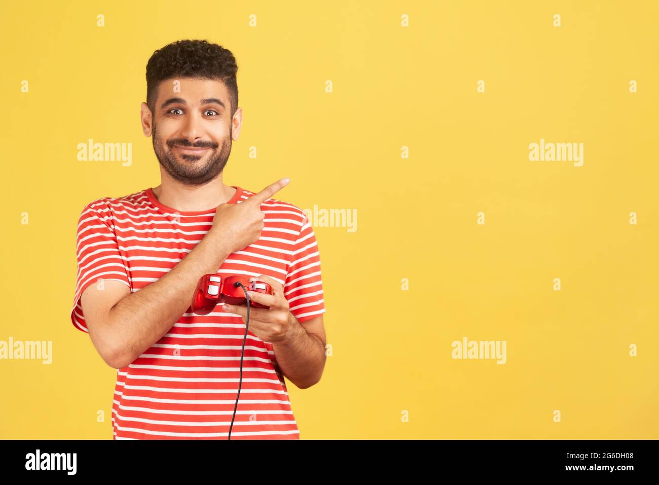 Smiling positive male gamer with beard in striped t-shirt holding ...