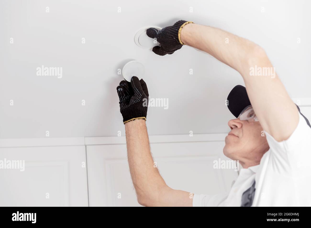 Electrician worker install replaces LED lighting lamp in apartment ...