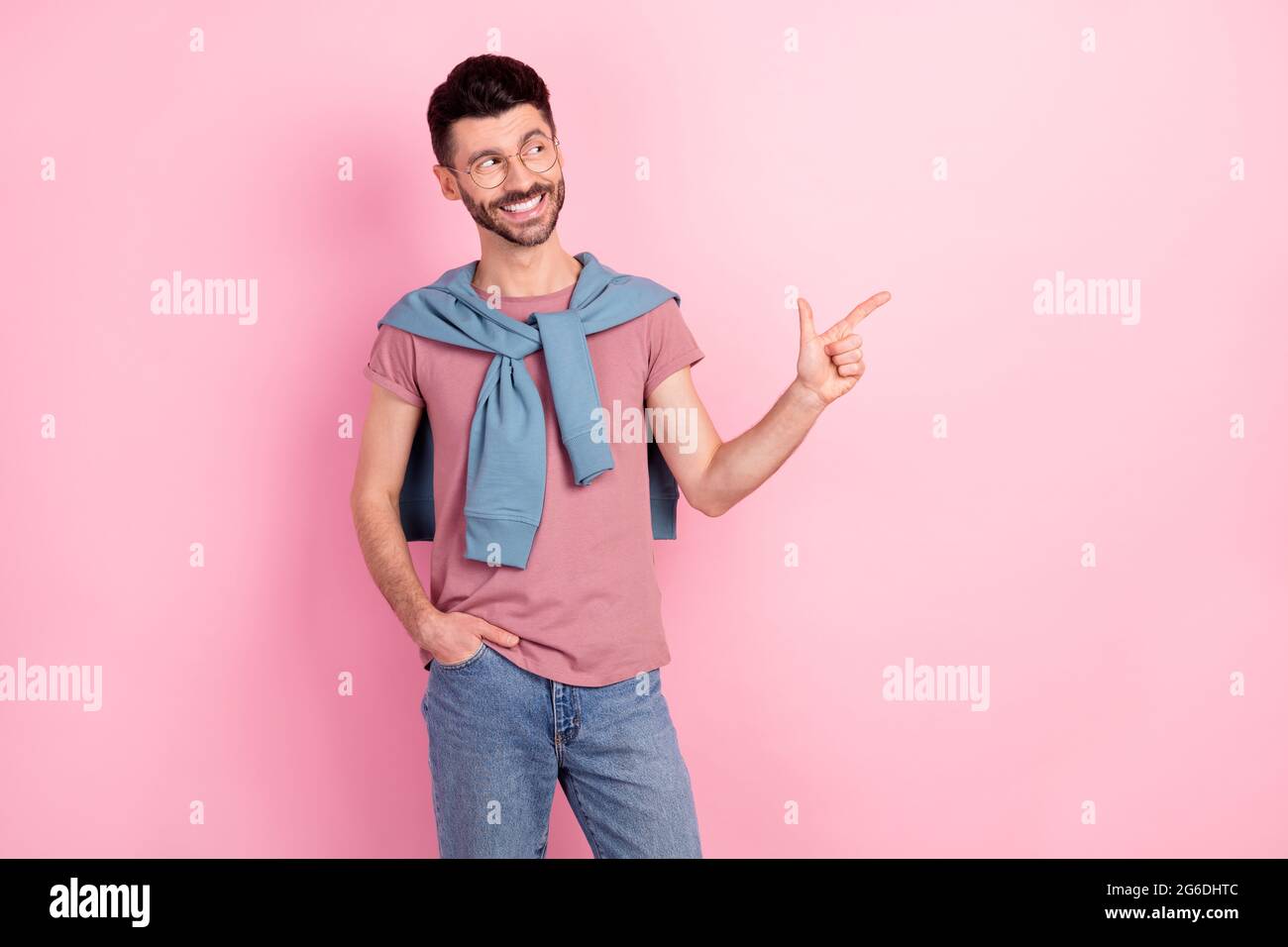 Photo of charming happy young dreamy man look empty space point finger ...