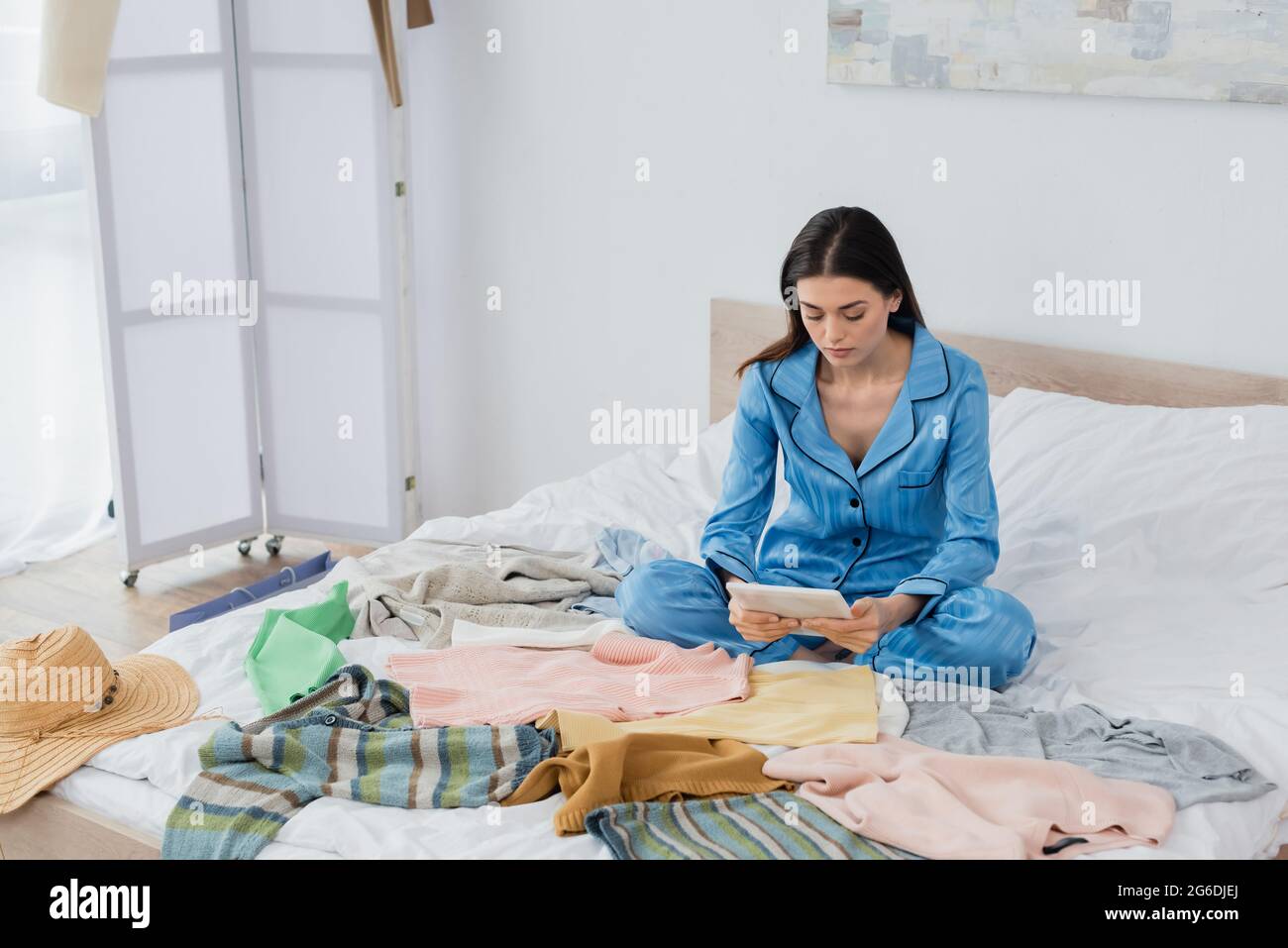 young woman in stylish pajama blogging on digital tablet while sitting ...
