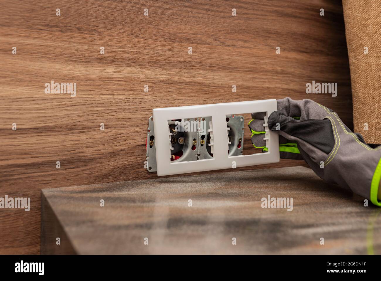 The electrician installs a decorative frame on the electrical outlets ...