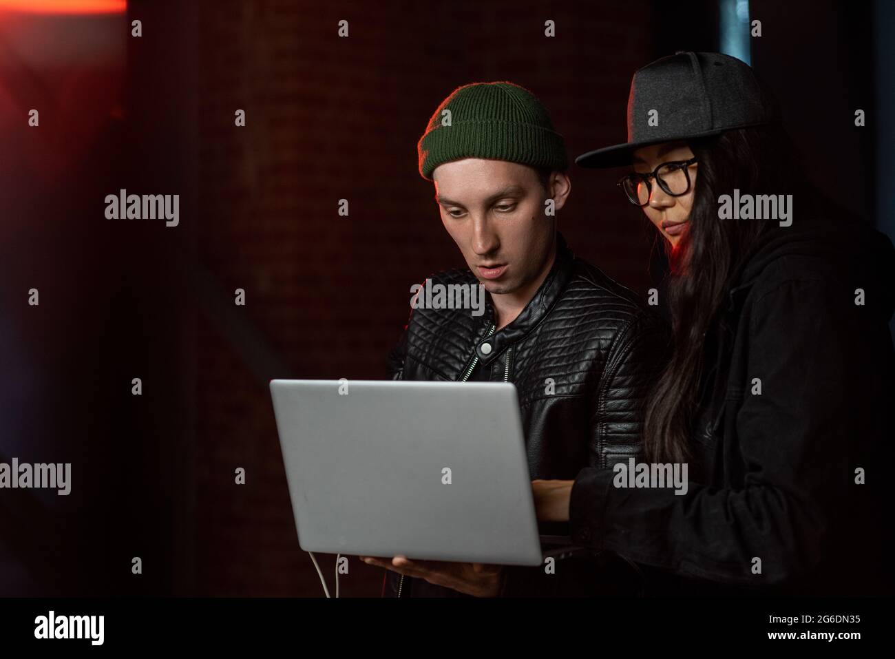 Two young hackers with laptop decoding information in the dark Stock ...