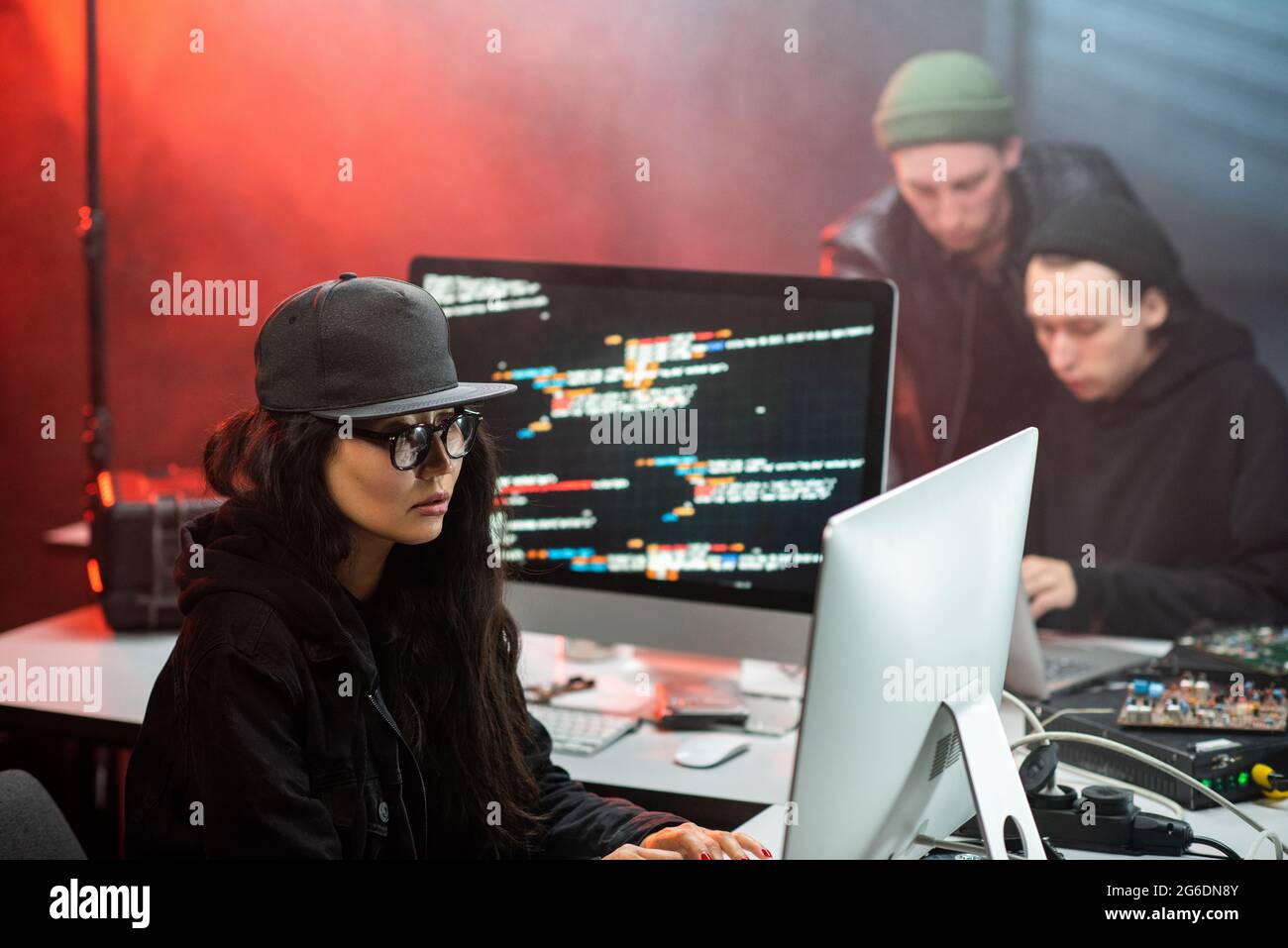 Young Asian woman in hacker attire and two guys decoding information ...