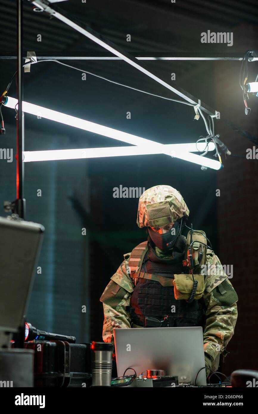 Hacker in camouflage attire using laptop while stealing information ...