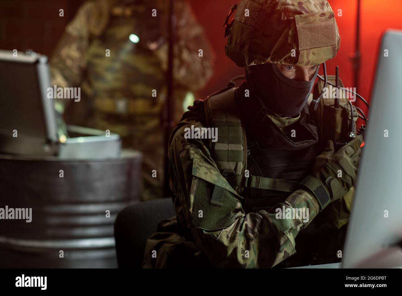 Cyber criminal with walkie-talkie looking attentively at computer ...