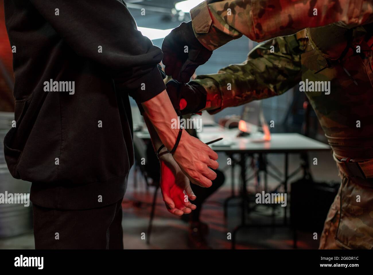 Officer in military outfit putting cuffs on hands of captured criminal ...