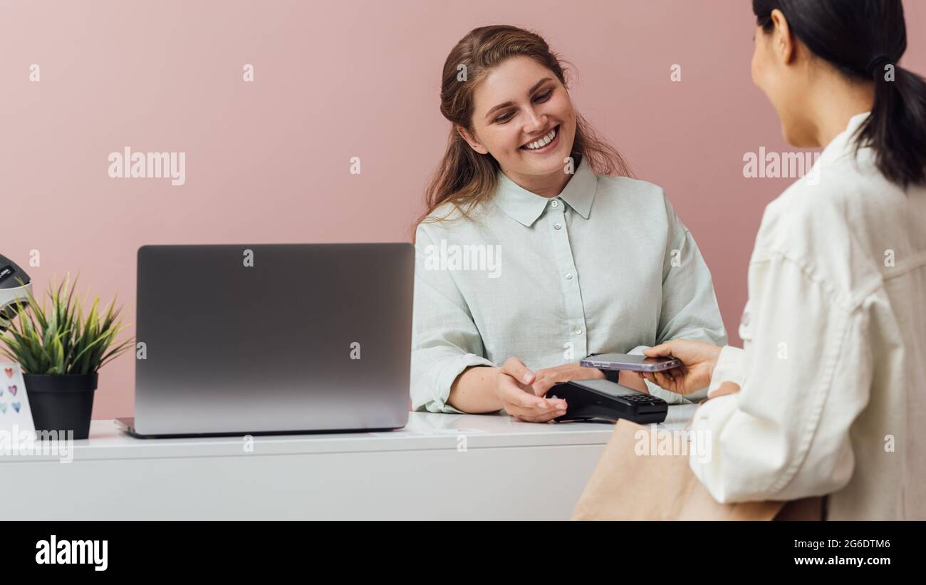 Happy clothing store owner giving pos terminal to buyer. Smiling ...