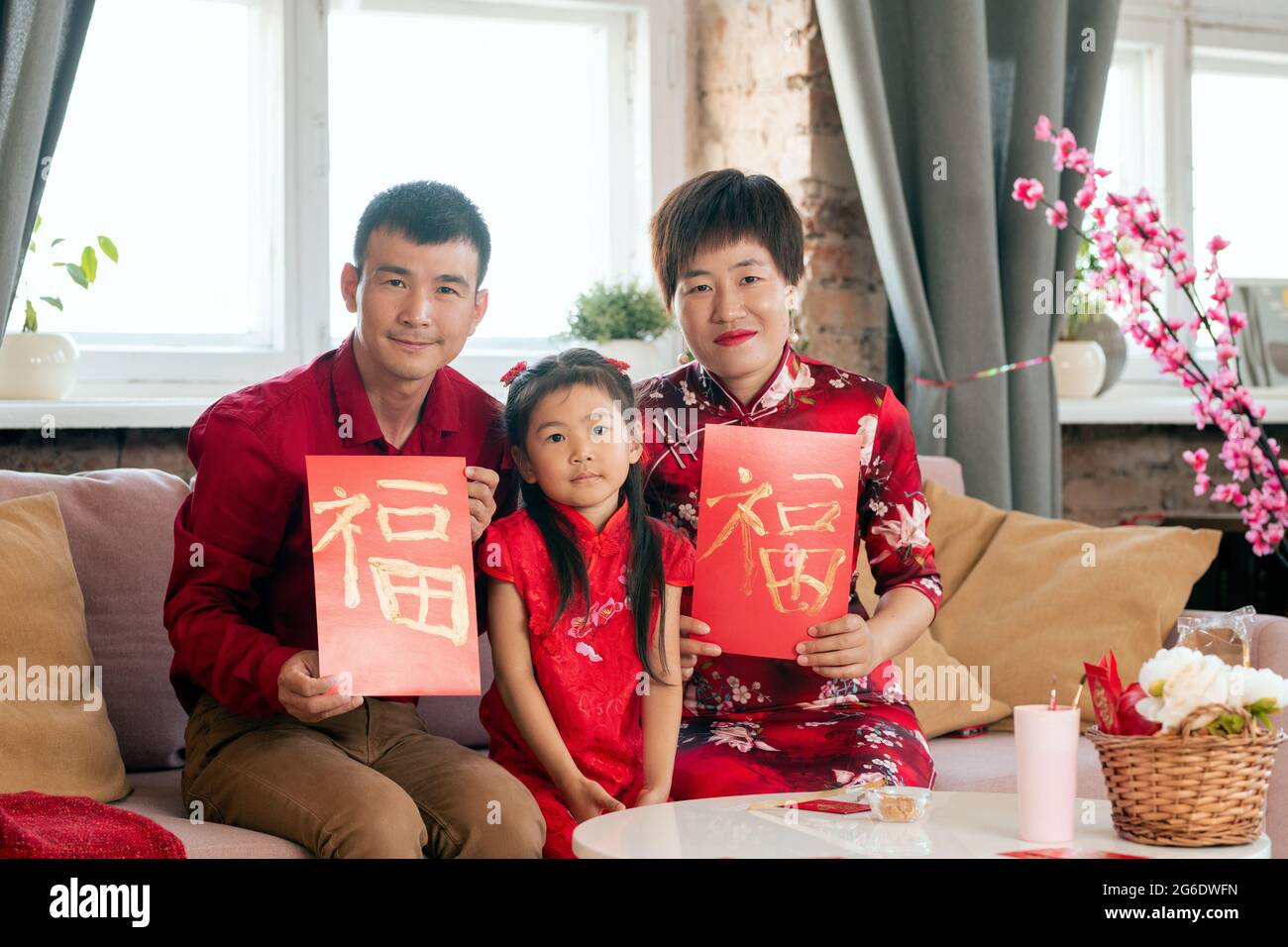 Three members of Chinese family showing handmade new year postcards ...