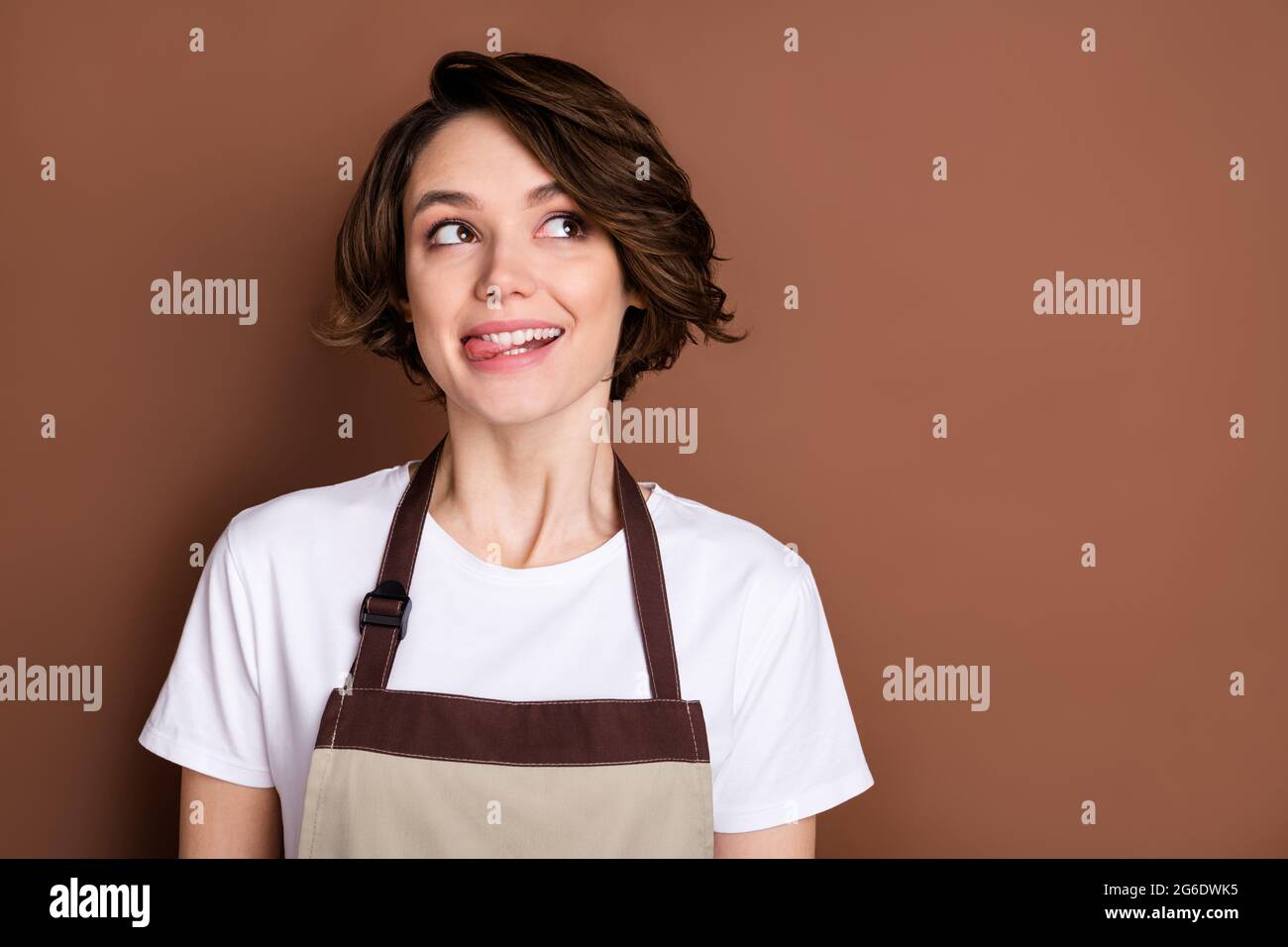 Portrait of pretty positive lady biting tongue look empty space have ...