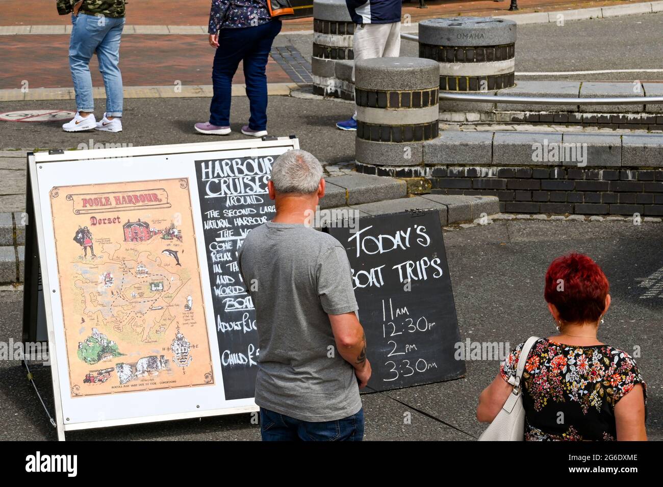 Poole, England - June 2021: People looking at signs advertising boat ...