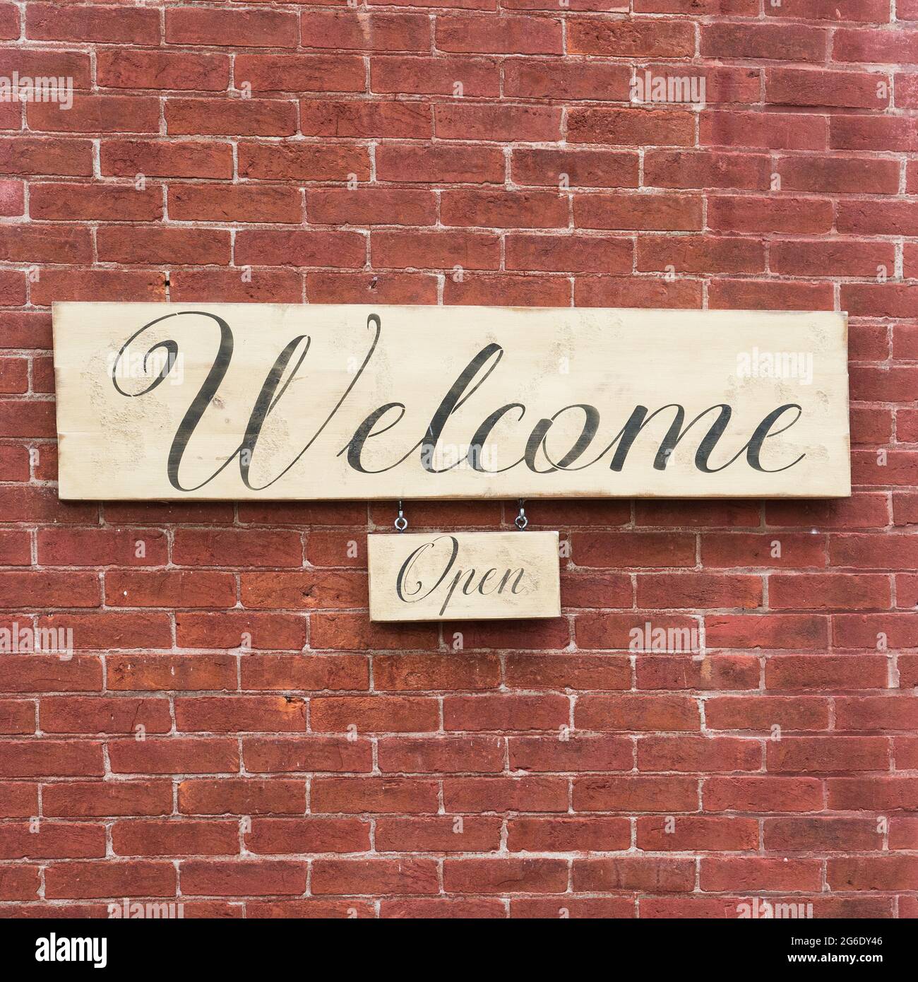 Welcome open signs in script text hanging on a red brick wall Stock ...