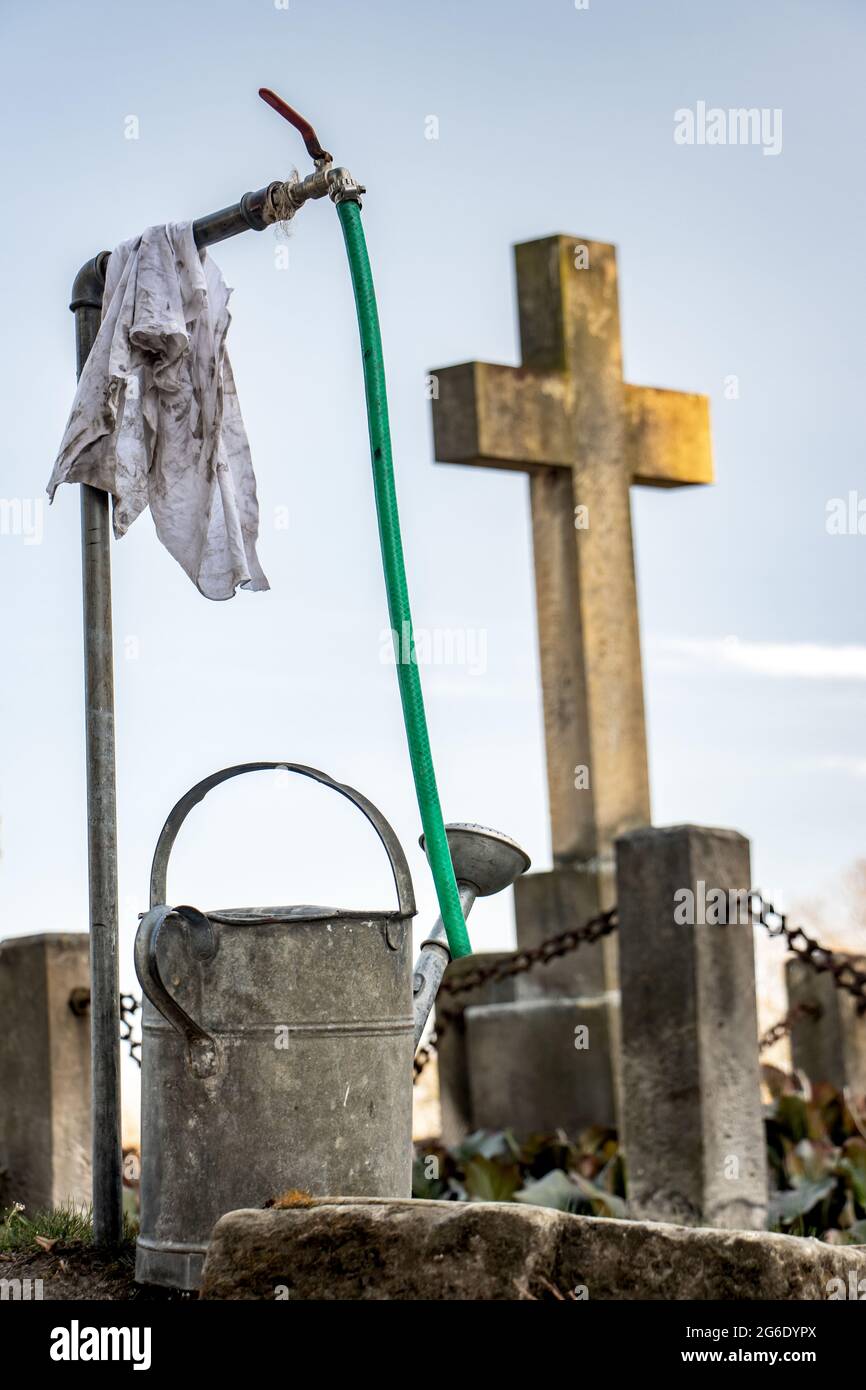 A water supply with watering cans in the cemetery Stock Photo - Alamy