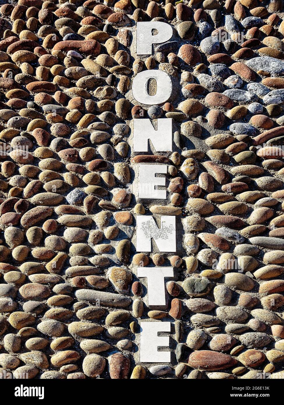 Lettering Ponente between rounded stones, street pavement in Cefalu ...
