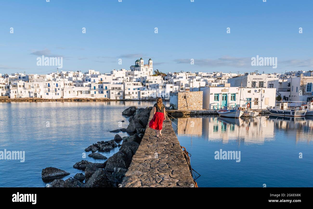 Young woman with red dress on harbour wall, harbour town Naoussa ...