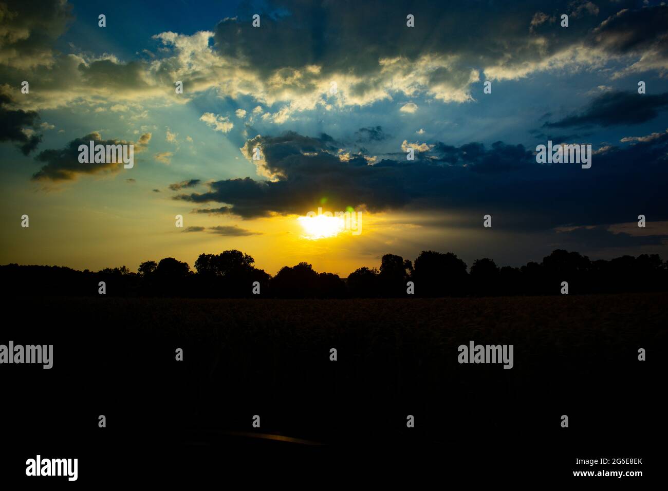 Sunset in field with clouds Stock Photo - Alamy