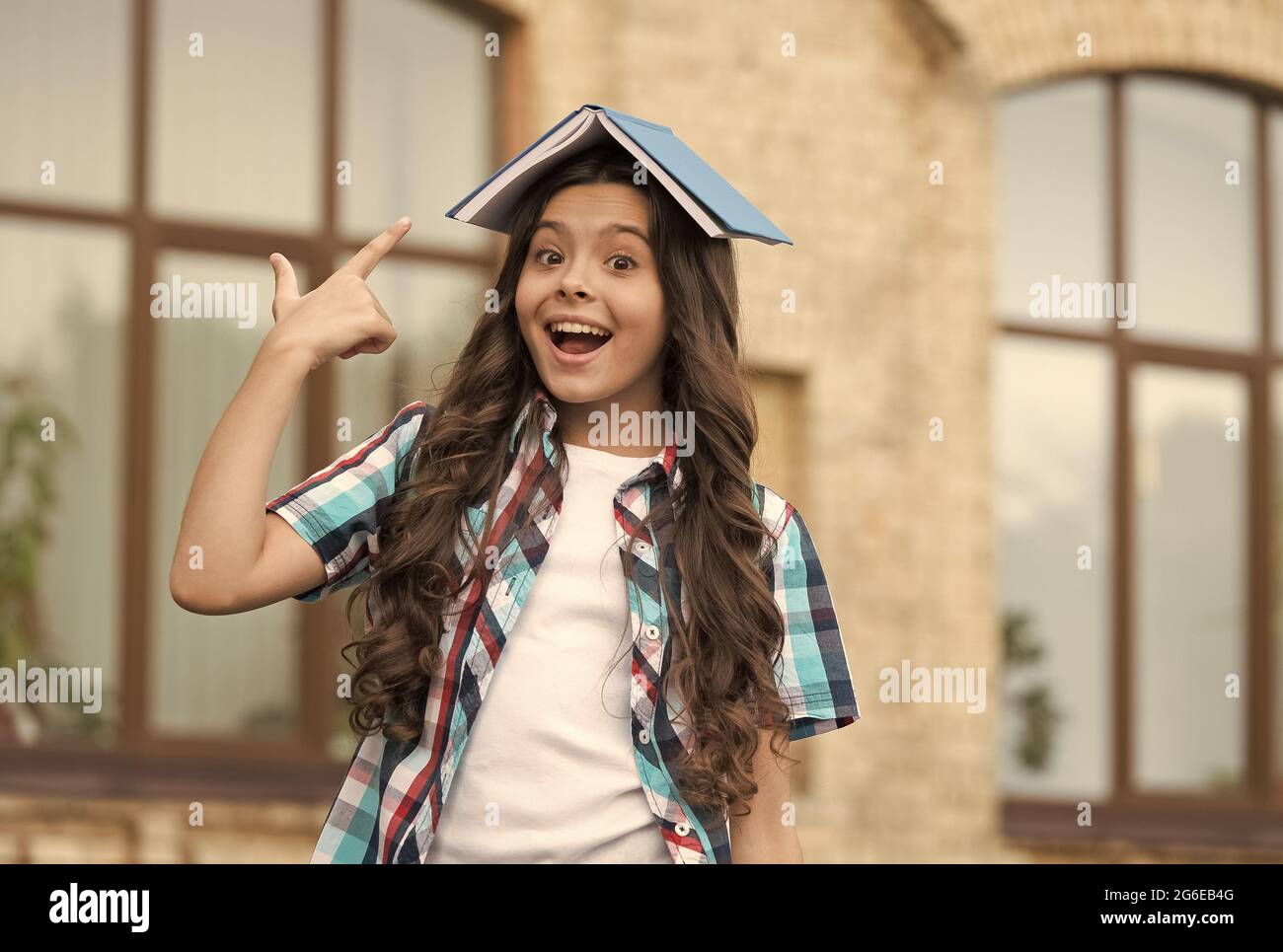 Reading for her own enjoyment. Happy child point at library book on ...