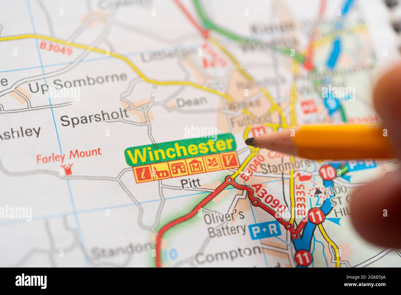 Closeup of a page in a printed road map atlas with a man's hand holding ...