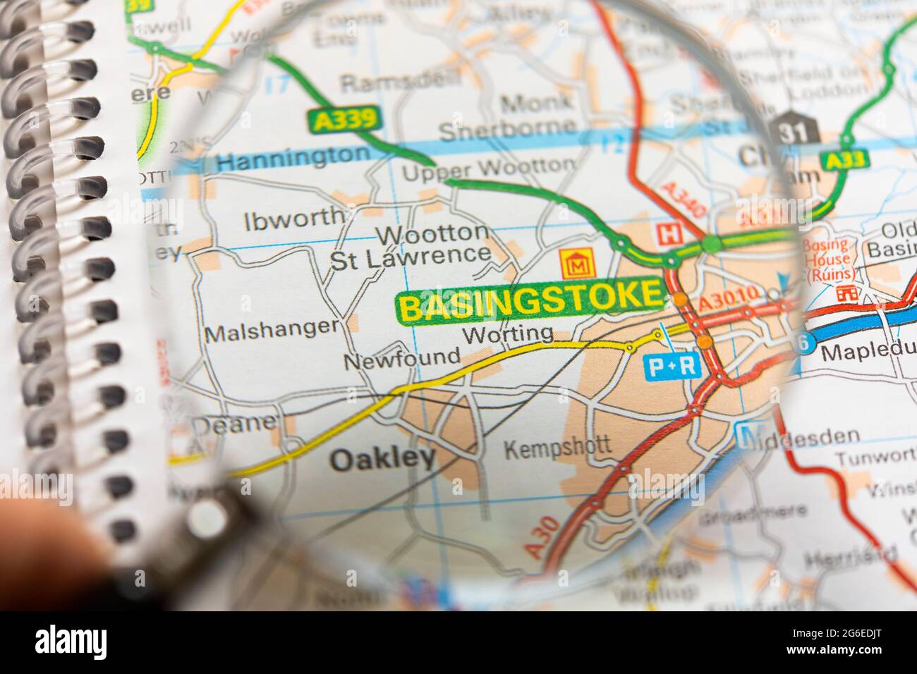 Closeup of a page in a printed road map atlas with a magnifying glass ...