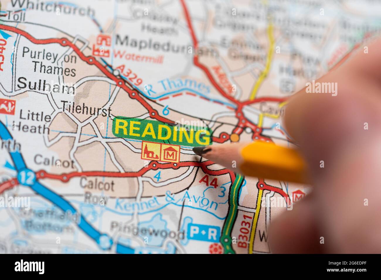 Closeup of a page in a printed road map atlas with a man's hand holding ...