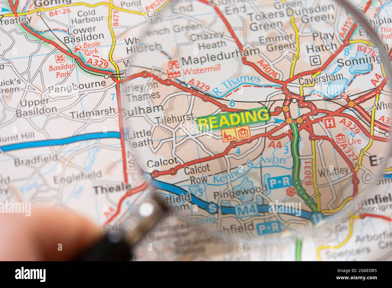 A macro closeup of a page in a printed road map atlas with a man's hand ...