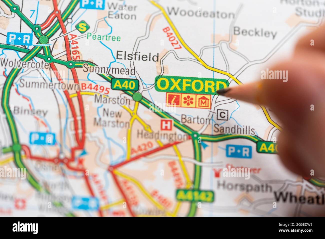Closeup of a page in a printed road map atlas with a man's hand holding ...