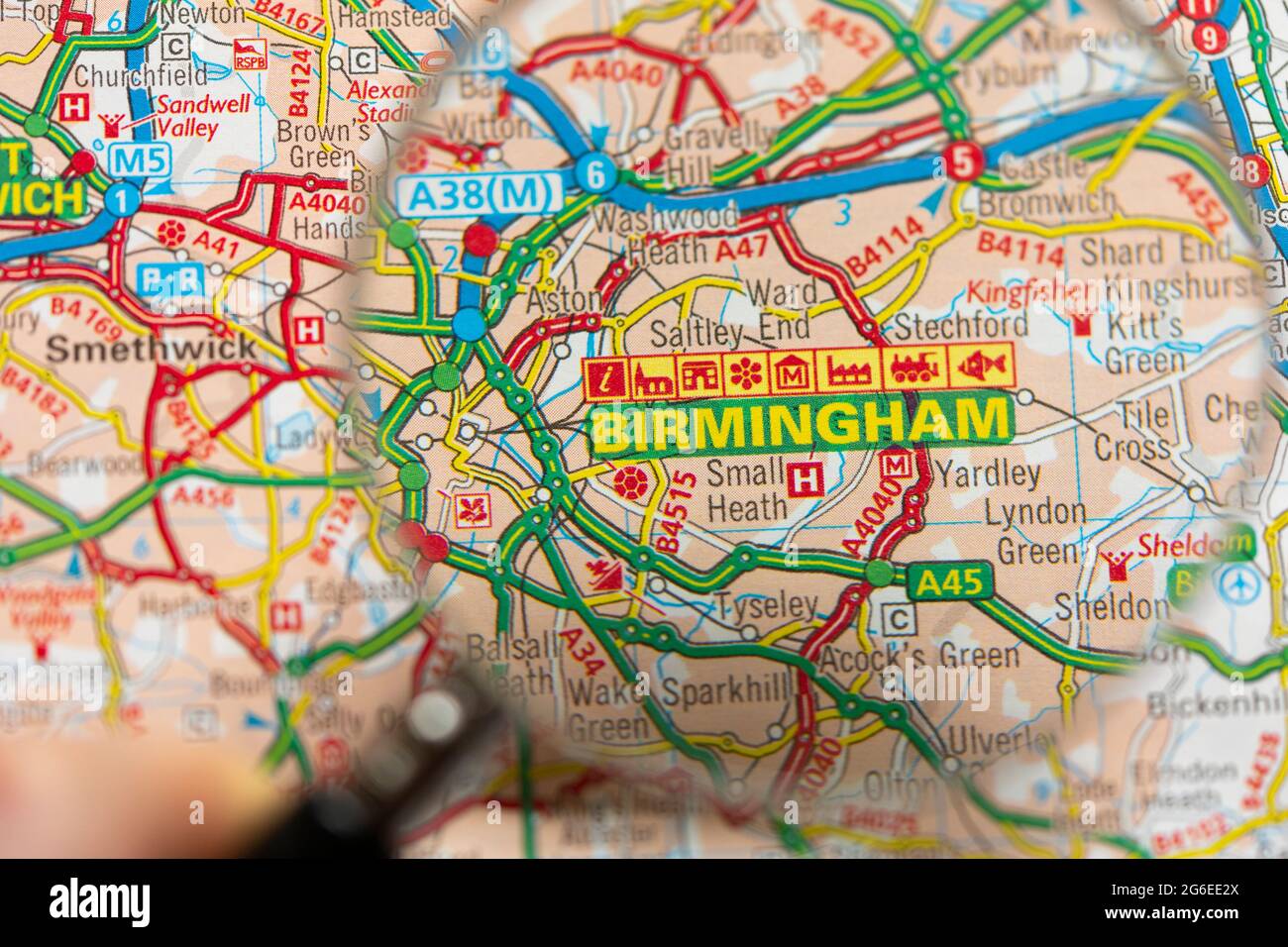 Closeup of a page in a printed road map atlas with a man's hand holding ...