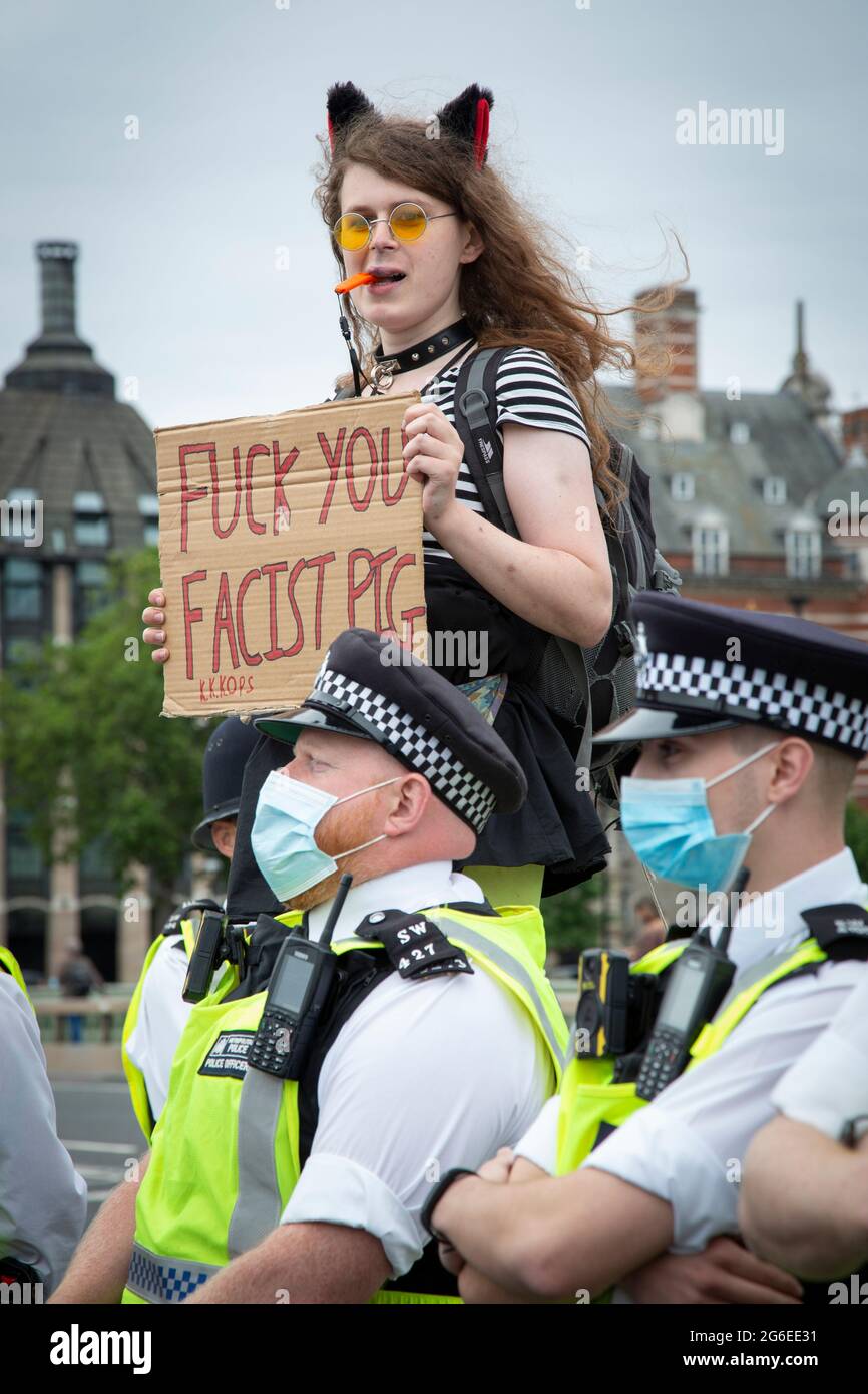 A young protester wearing cats ears and yellow glasses holds up a sign ...