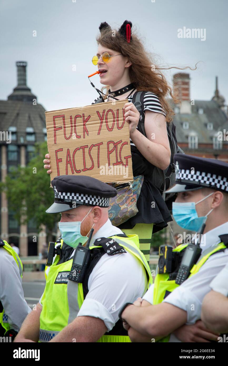 A young protester wearing cats ears and yellow glasses holds up a sign ...