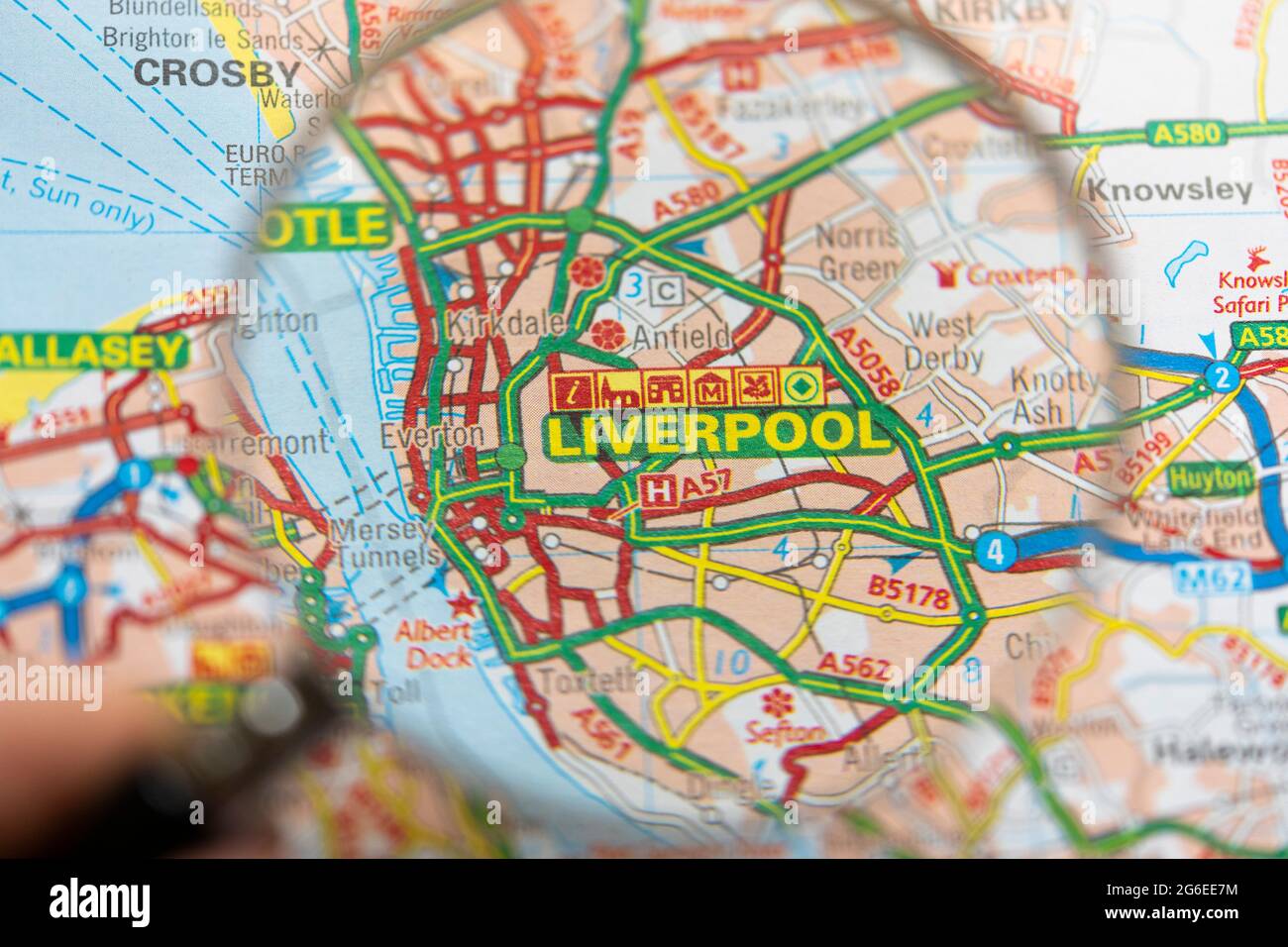 A macro closeup of a page in a printed road map atlas with a man's hand ...