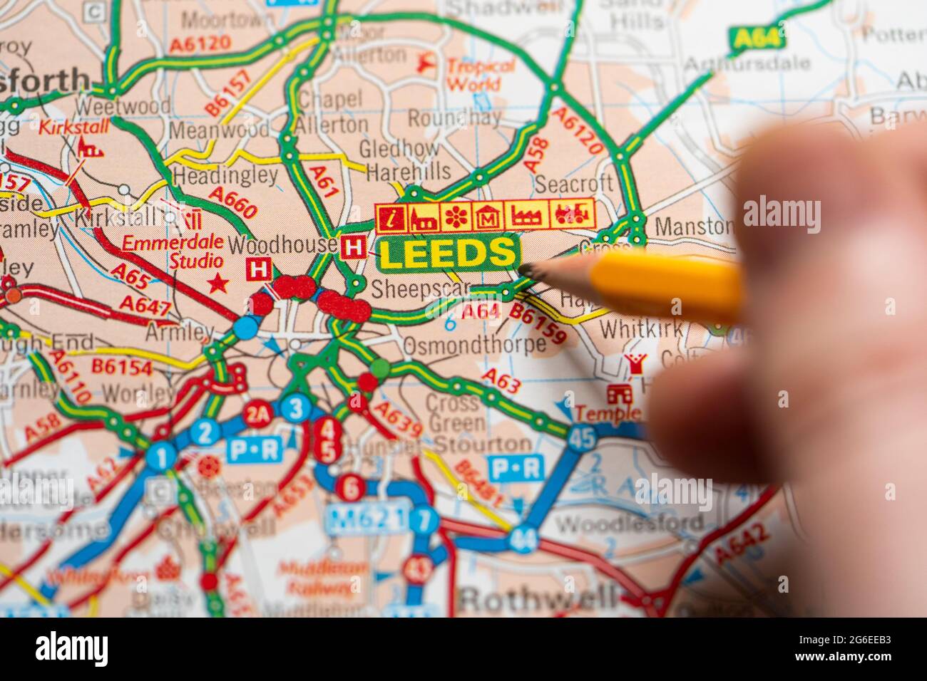 Macro closeup of a page in a printed road map atlas with a man's hand ...