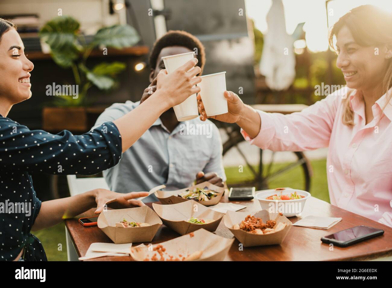 Happy people eating and cheering at food truck restaurant - Focus on ...