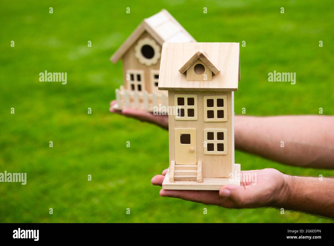 Neighbors house concept. House in hand against spring green background ...